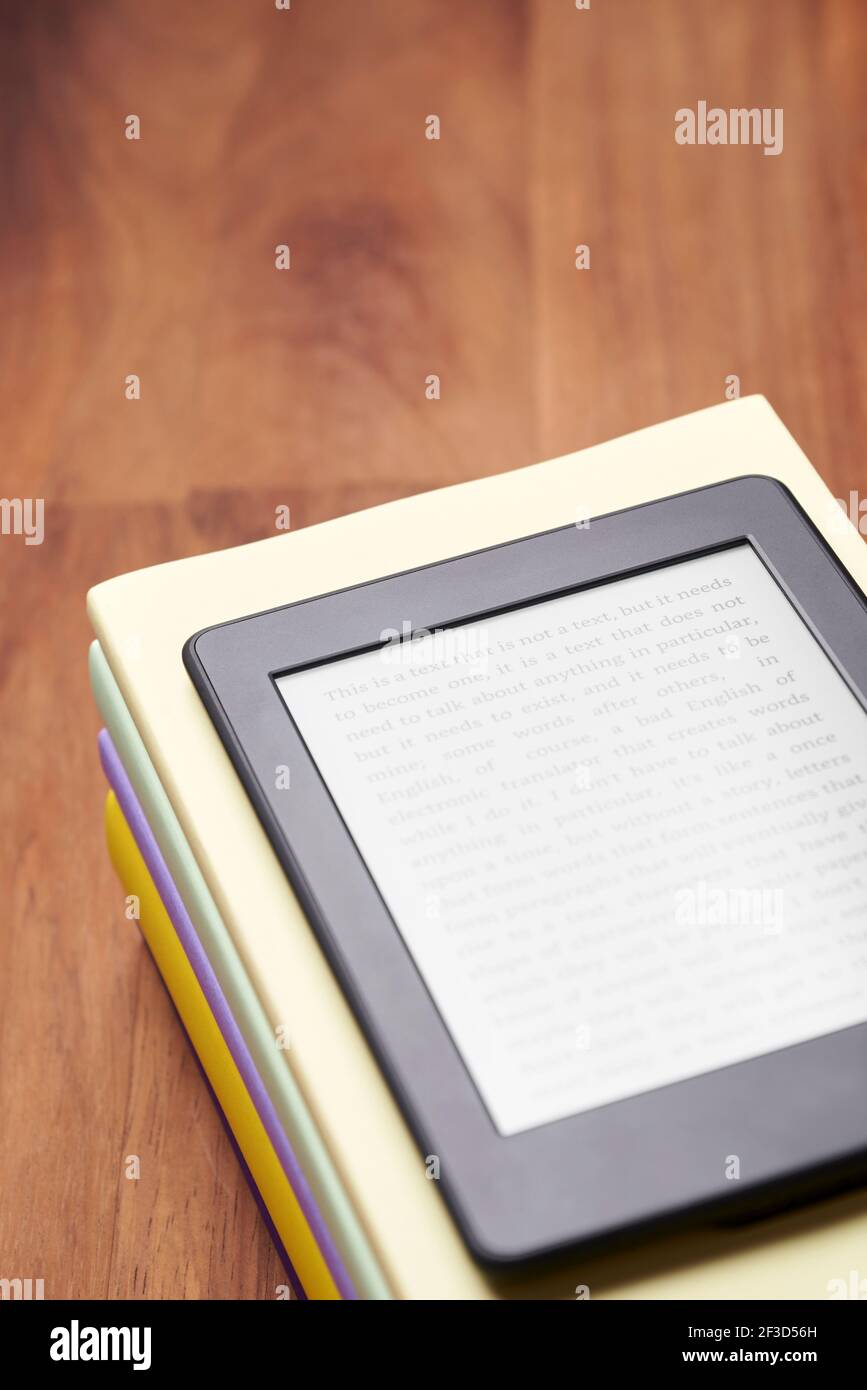 Electronic reader with a text on the screen on a stack of books on a ...