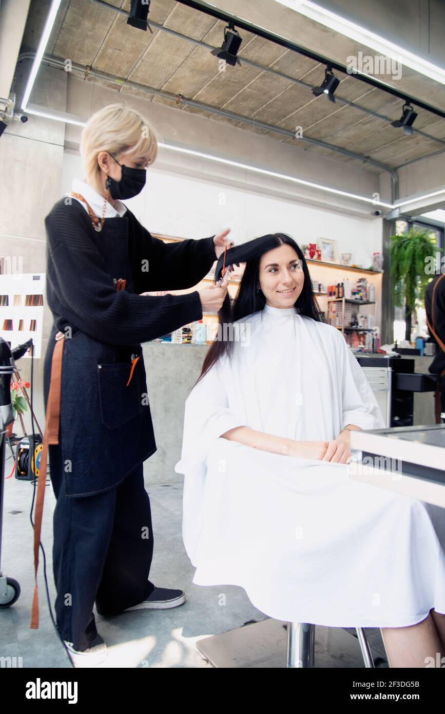 Asian female hairdresser make hairstyles for female customers in modern ...