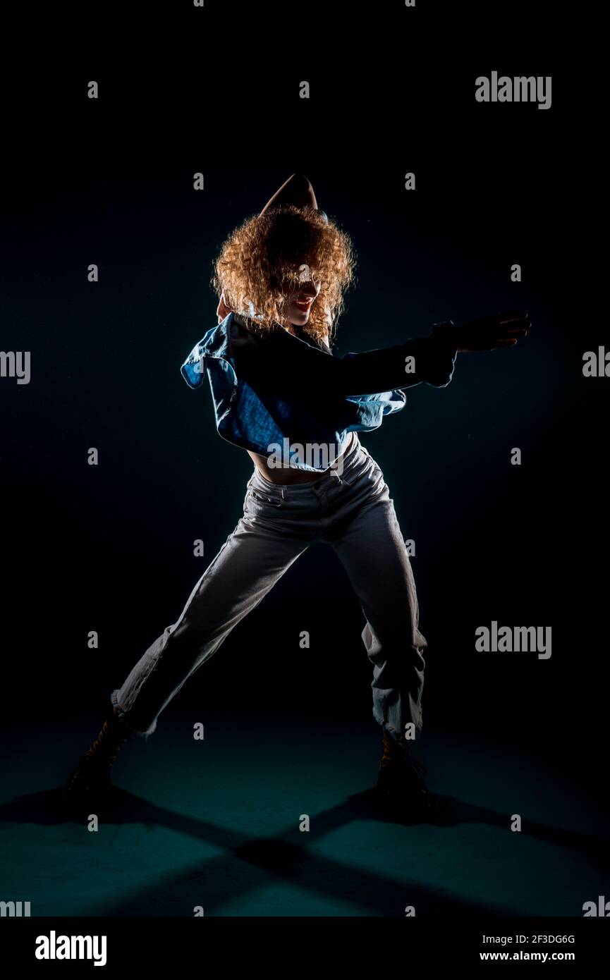 Fit young girl dancer performing a dance routine isolated in the dark ...