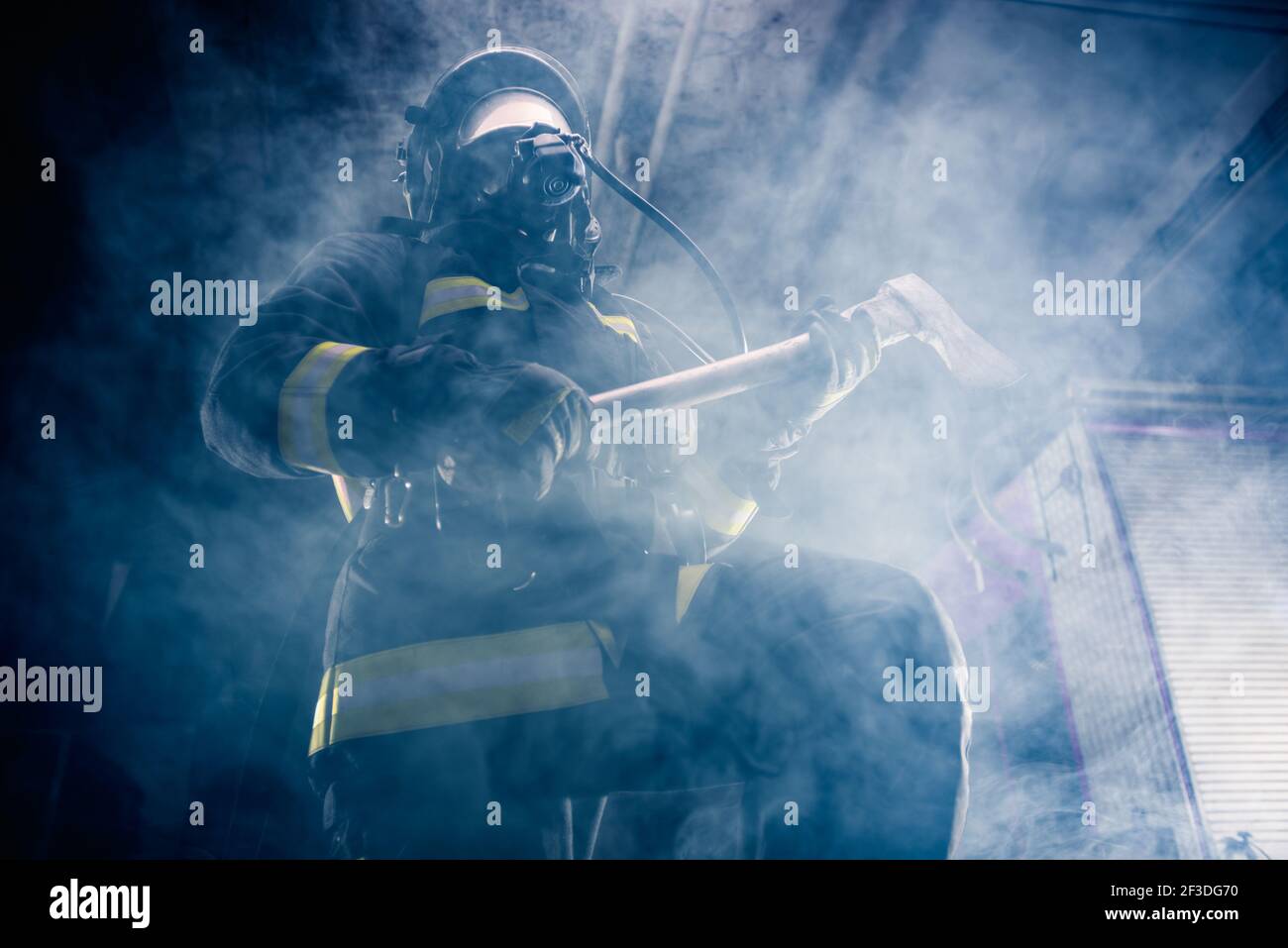 Portrait of a female firefighter while holding an axe and wearing an ...