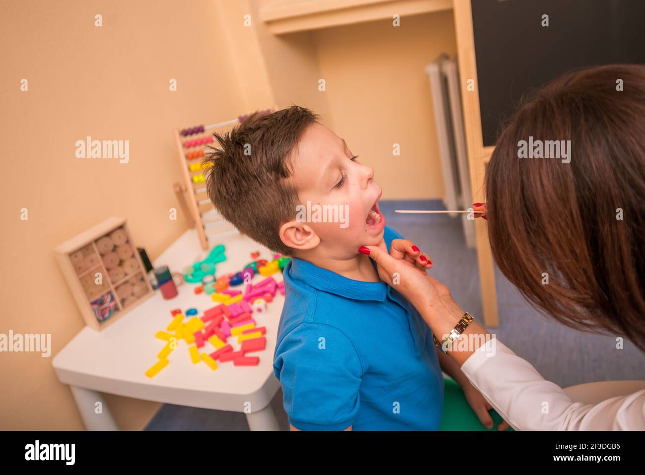 Female Pediatrician check's the throat and mouth of a young cute boy ...