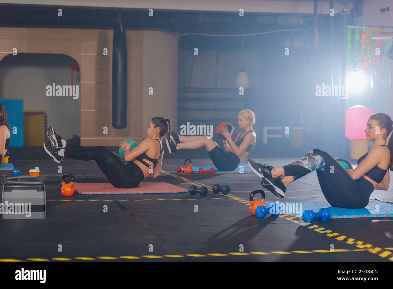 Side view of beautiful young women exercising russian twist with ...