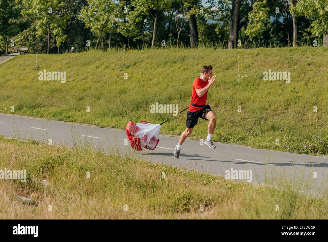 Side view of a strong man doing workout using resistance parachute ...