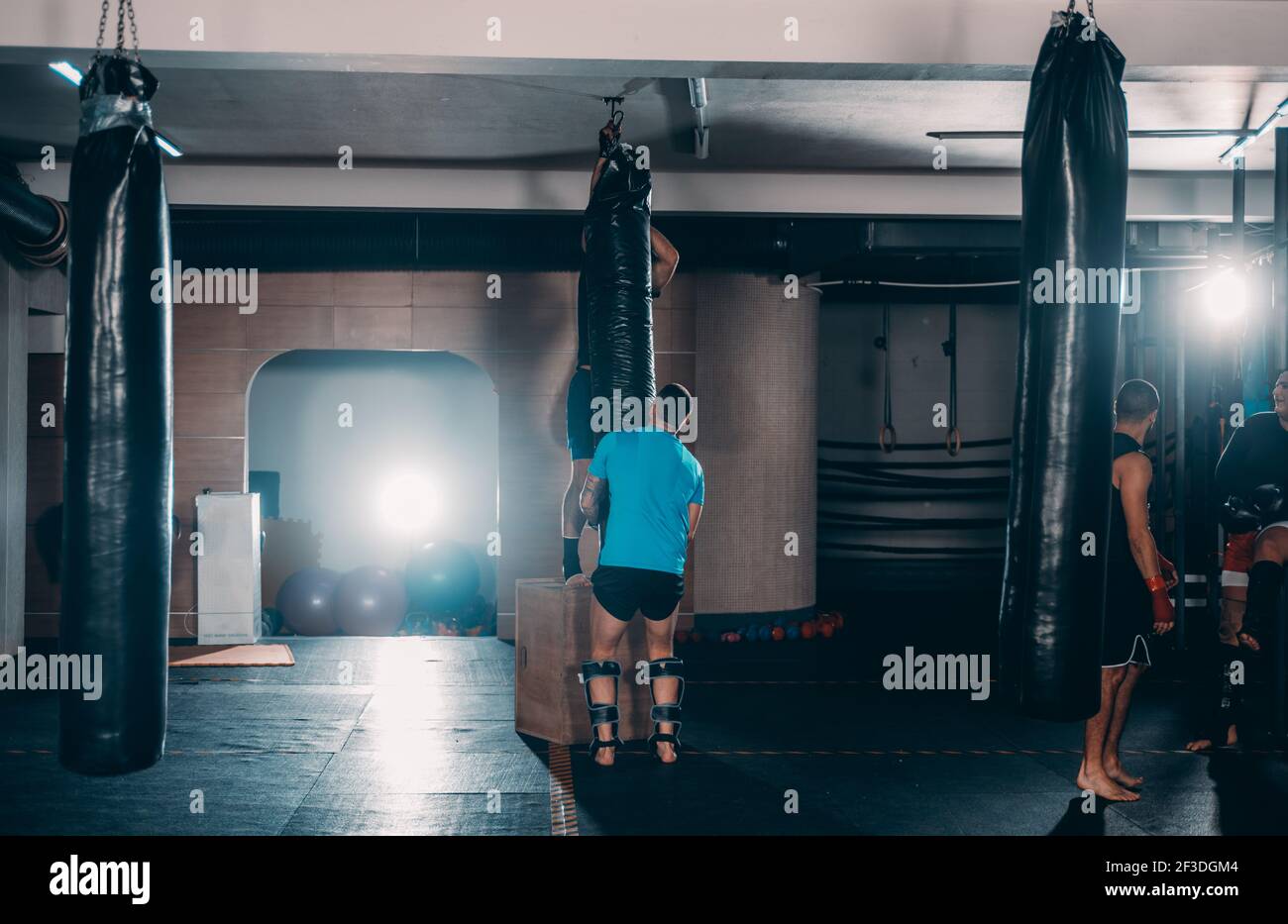 Sporty man set up boxing bag on the wall in underground garage Stock ...