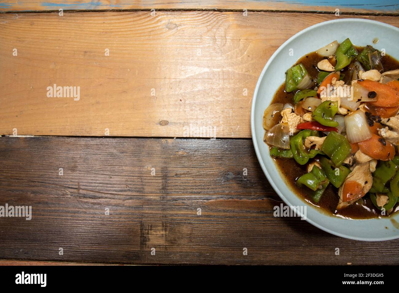 A delicious bowl of Chicken with Green pepper Stir Fry on a wooden ...
