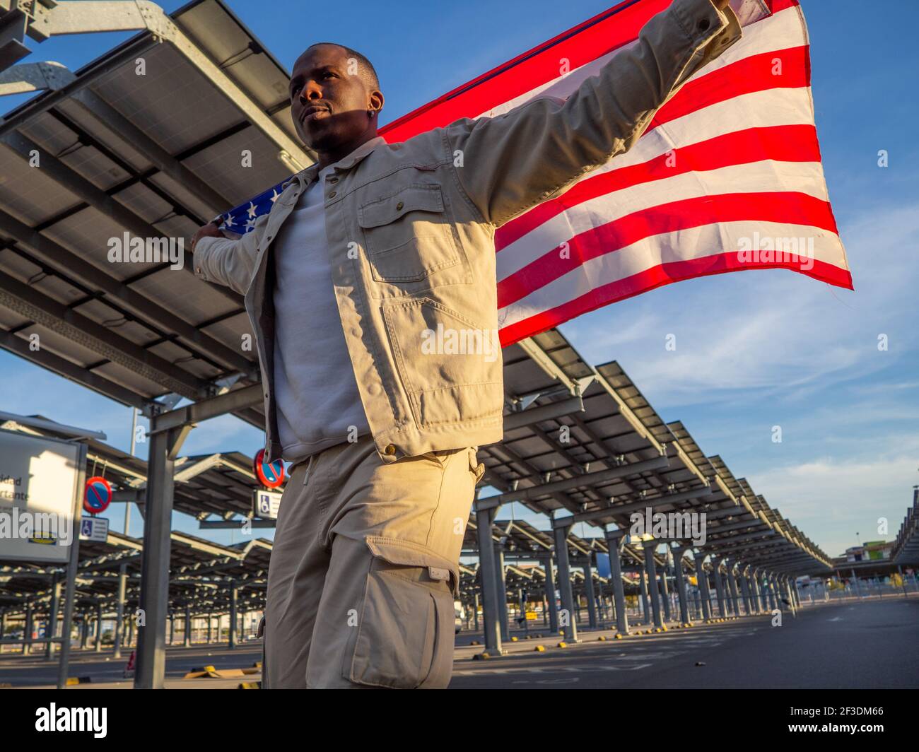 A handsome black Spanish male with hands up holds a flag of the USA ...
