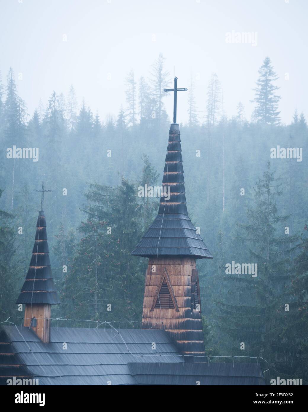 Close-up of two chapel towers with conifer forest in background ...
