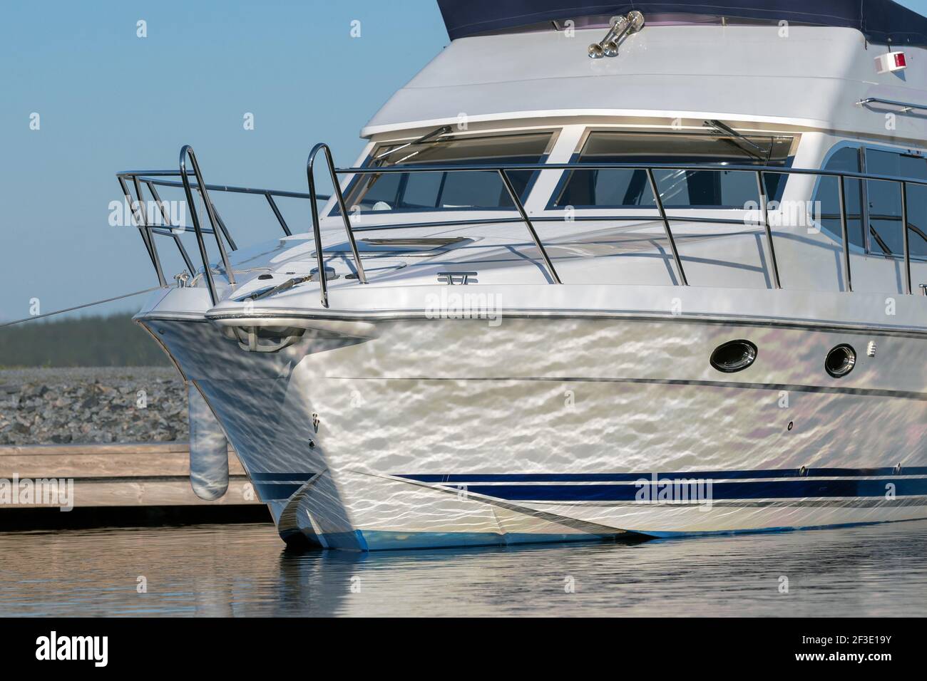 A white yacht attached to the dock and the water reflected on the boat ...