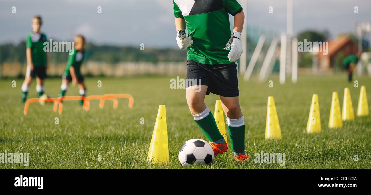 Kid soccer player dribbling through cones. Boy in soccer uniform ...