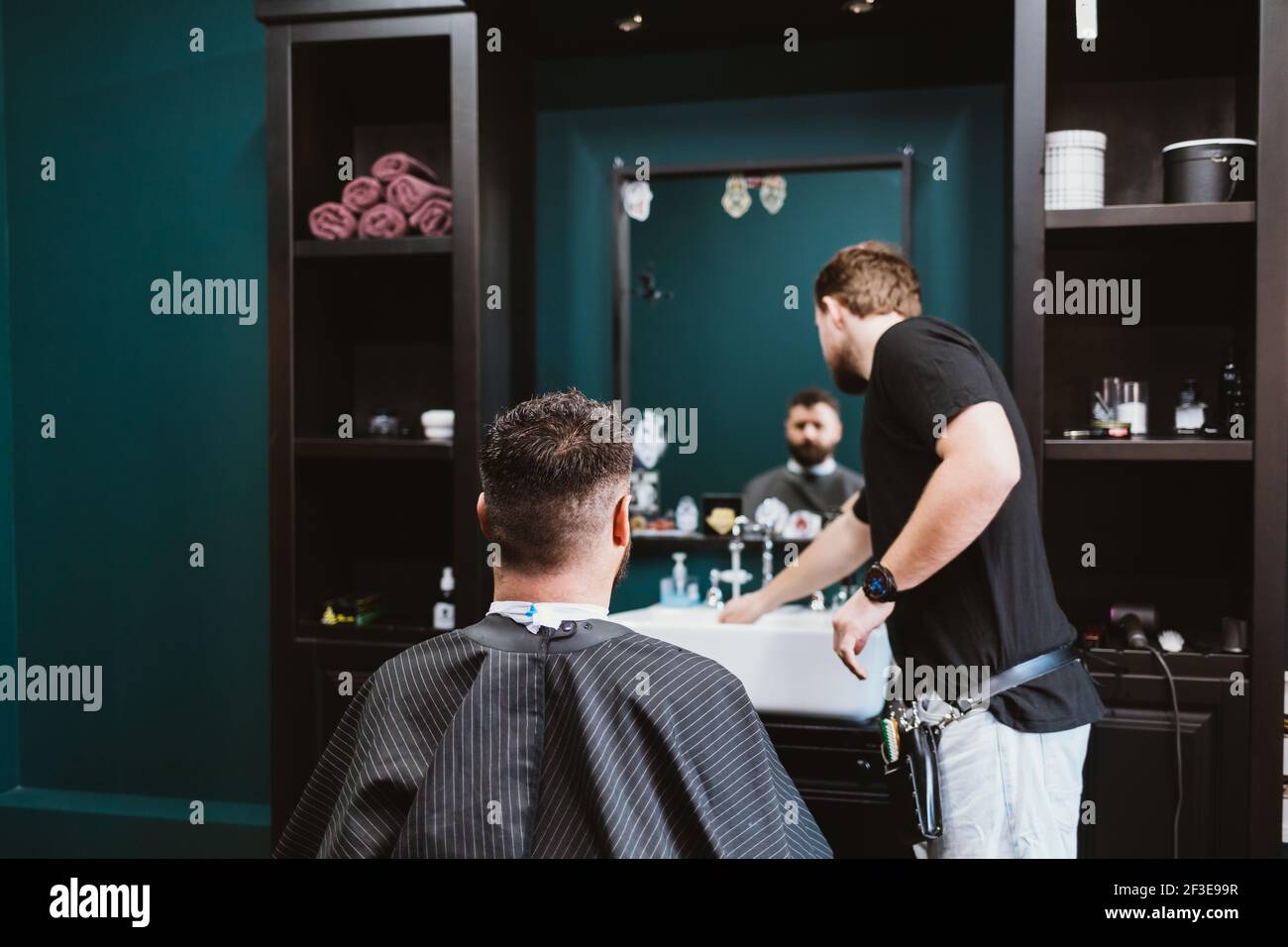 Barber making haircut to male client, process of serving visitor in ...
