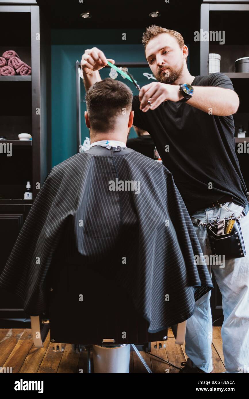 Men's haircut process, hairdresser cutting hair of male client who sits ...
