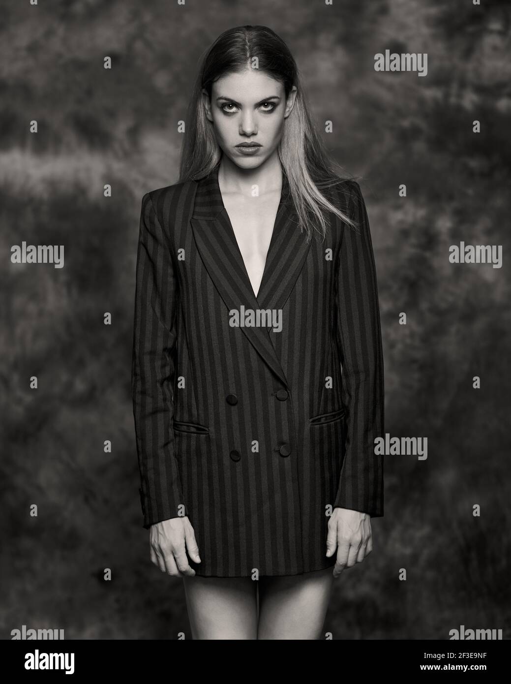 Studio portrait of a blonde woman standing with a jacket and ruined ...