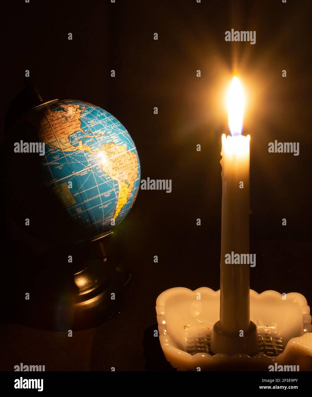 A vertical shot of a burning candle with a globe isolated on a dark ...