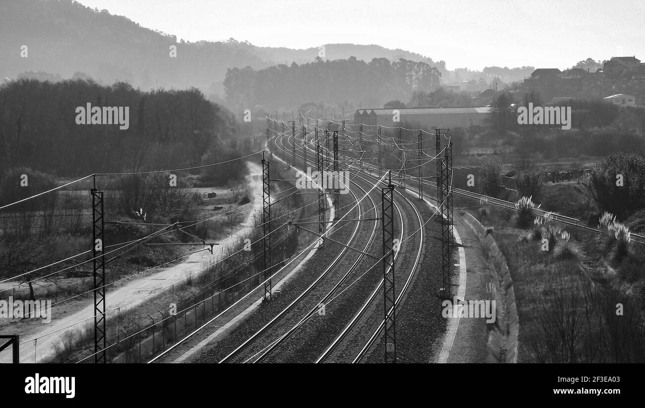 A grayscale shot of train tracks leading into the fog, a landscape that ...