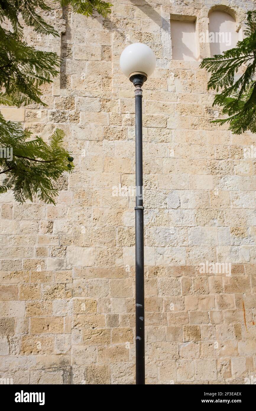 Lamp post against a stone wall backdrop Stock Photo - Alamy