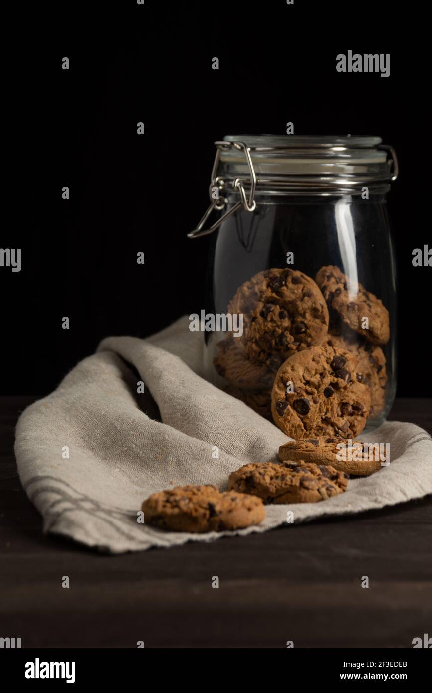 View of glass jar with cookies on cloth on wooden table, on black ...