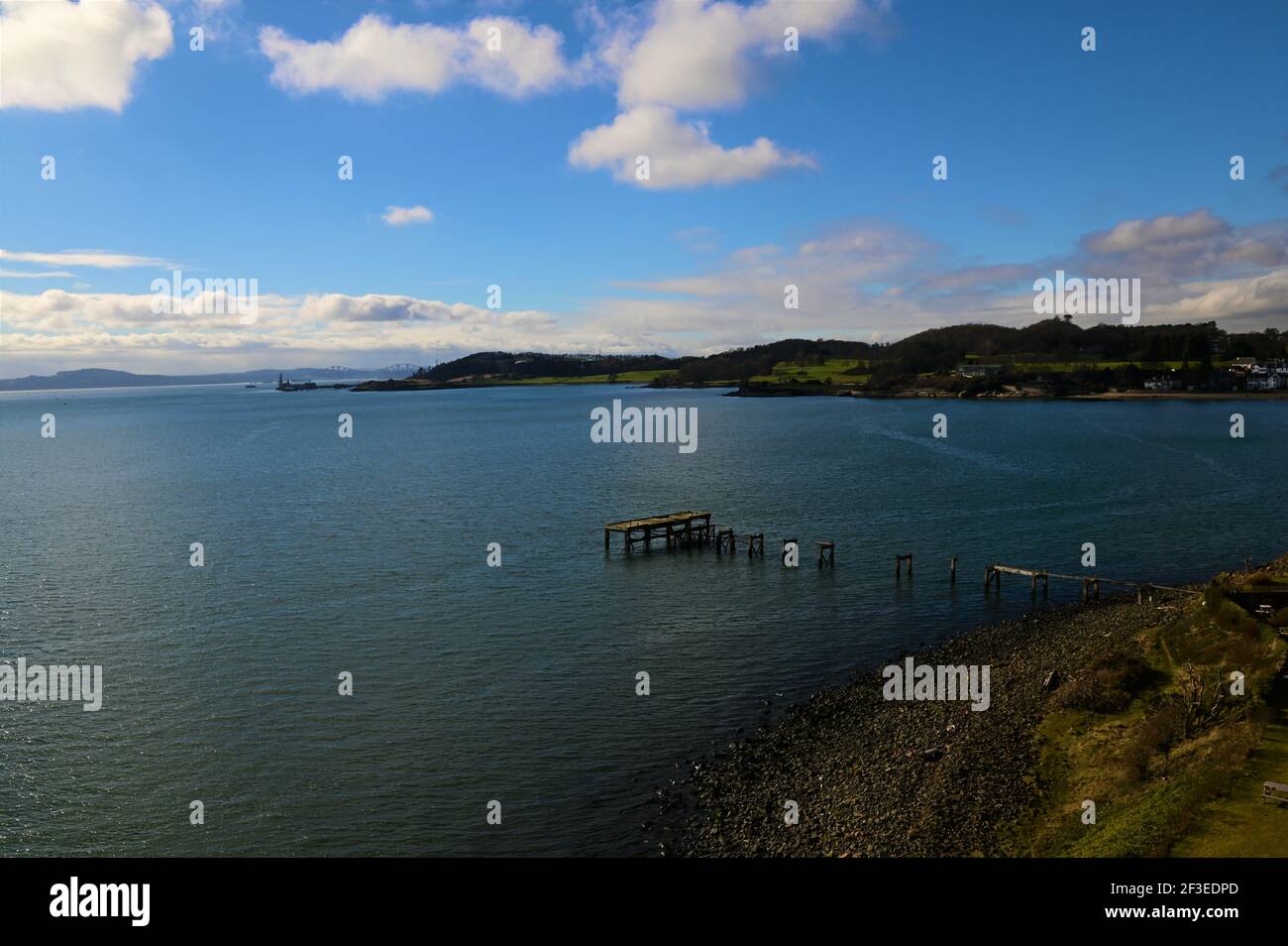 A view of the rocky coastline and old wooden pier at Aberdour on the ...