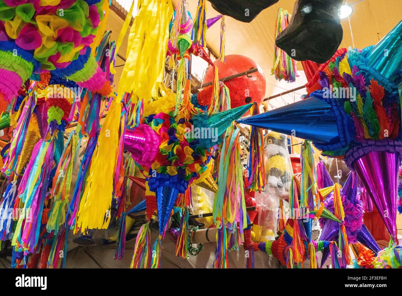Colorful pinatas with paper stripes hanging inside a market Stock Photo ...