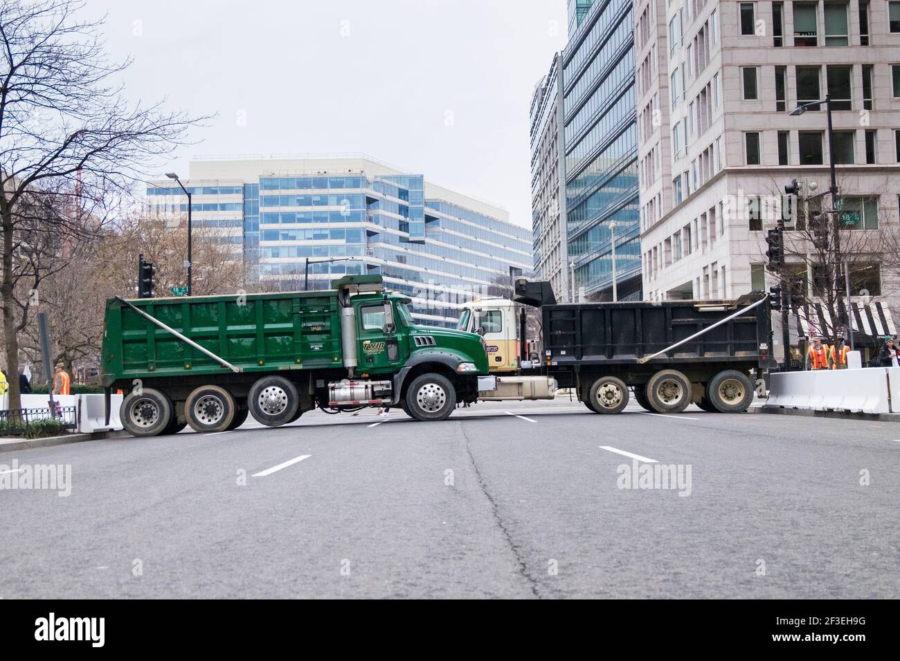 Large, heavy dump, construction trucks block the street as a security ...