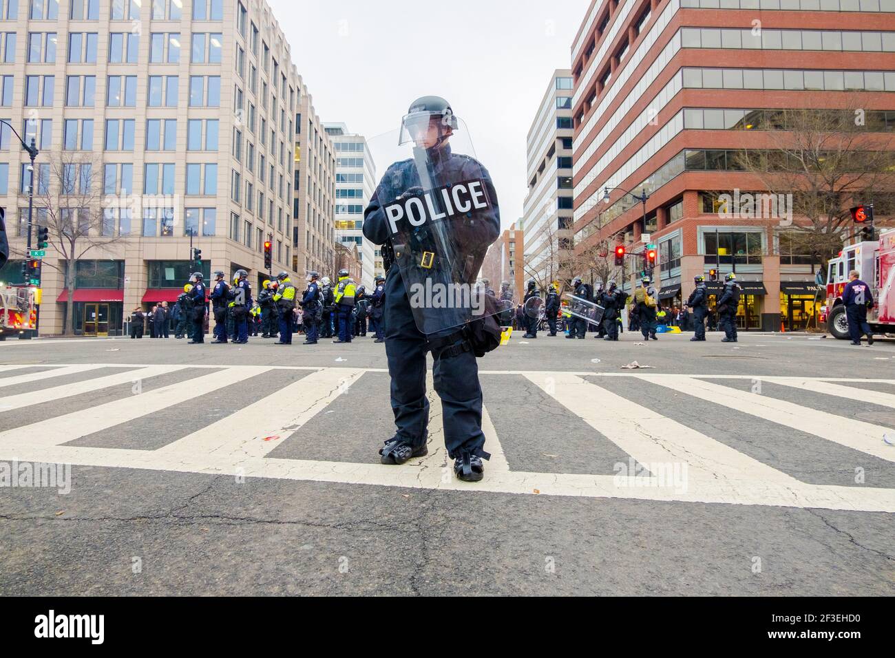 A lone police riot officer with sheild at a crosswalk intersection near ...