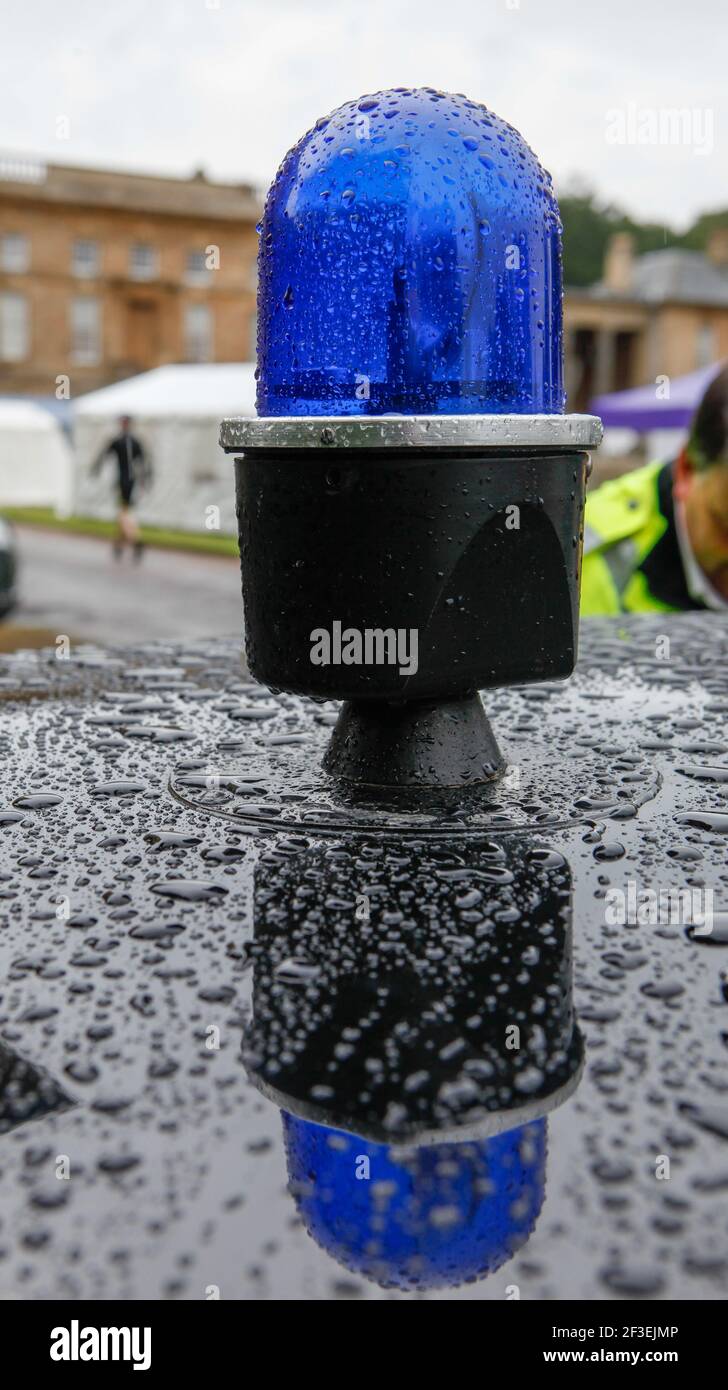 Blue light on the roof of a vintage police car on a wet day with ...