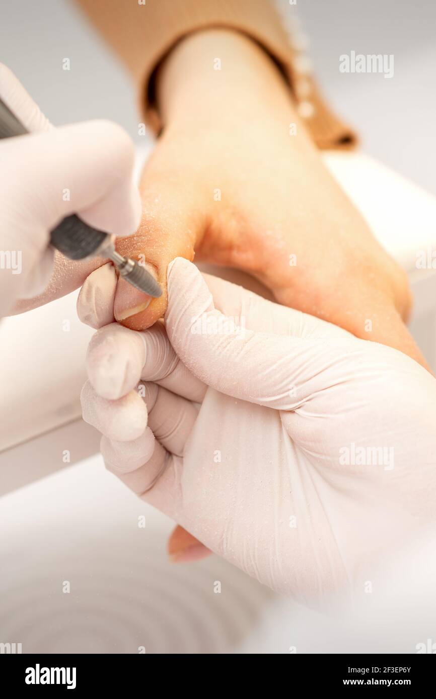 Manicure master applying electric nail file machine removing old nail ...