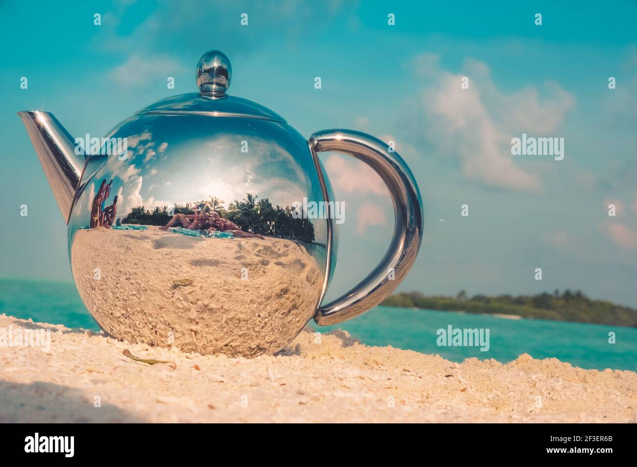 stainless steel teapot on a tropical beach. unrecognizable people ...
