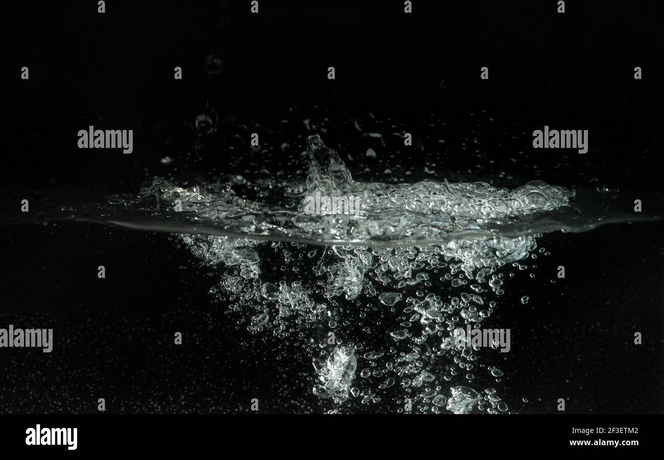 Water splashing as it's poured into aquarium tank, black background ...