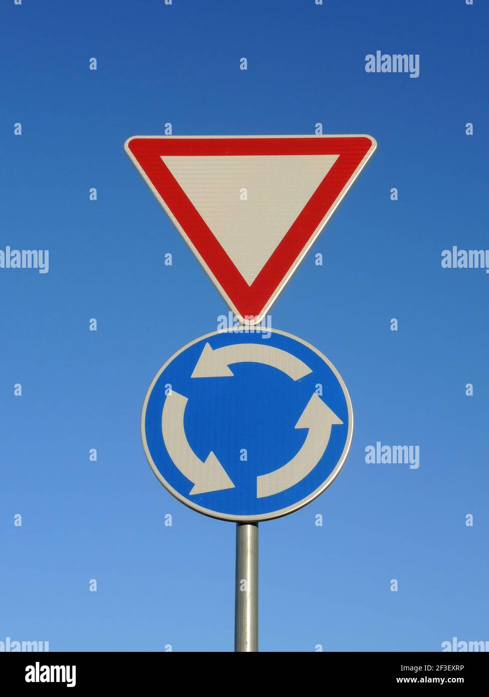 A vertical shot of two traffic signs on the same post - Give way and ...