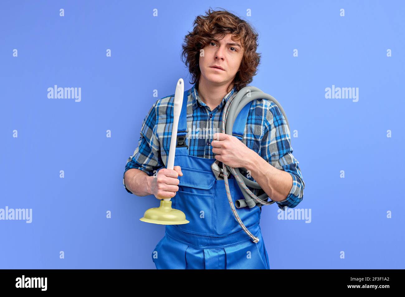confident plumber man with curly hair in uniform holding toilet plunger ...