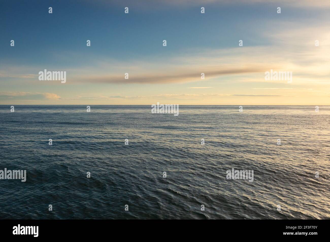 A beautiful view of the wavy ocean gleaming under the cloudy blue sky ...