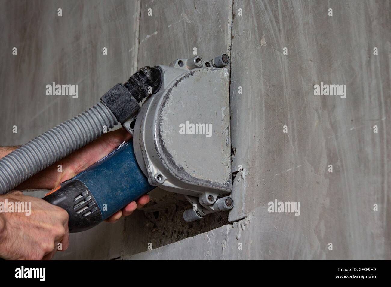 cutting a wall with a power tool at a construction site using a vacuum ...