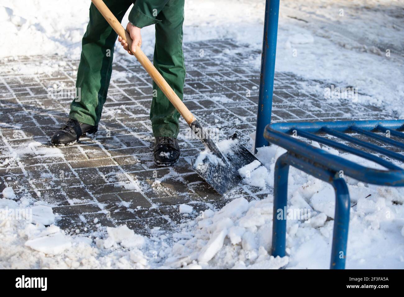 A worker uses a metal spade to break frozen pieces of ice off the ...