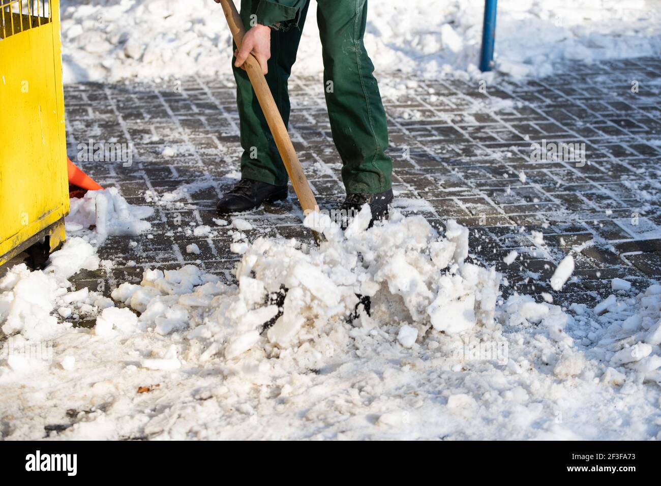 A worker uses a metal spade to break frozen pieces of ice off the ...