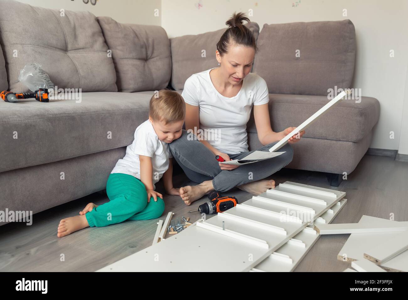 Cute adorable caucasian toddler boy kid sit on floor and help mom ...