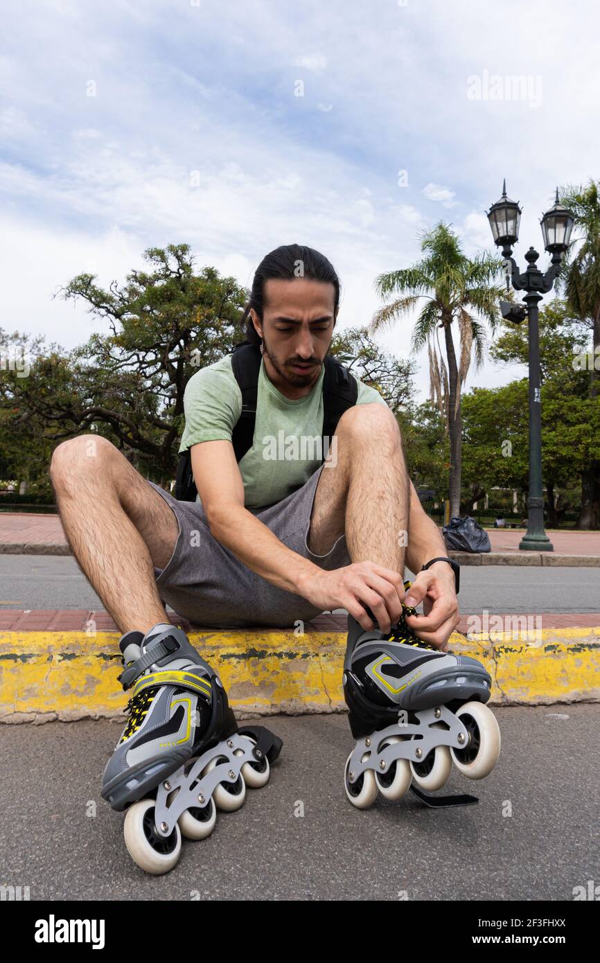 young man with long hair tying his rollers in a park. dispersion time ...