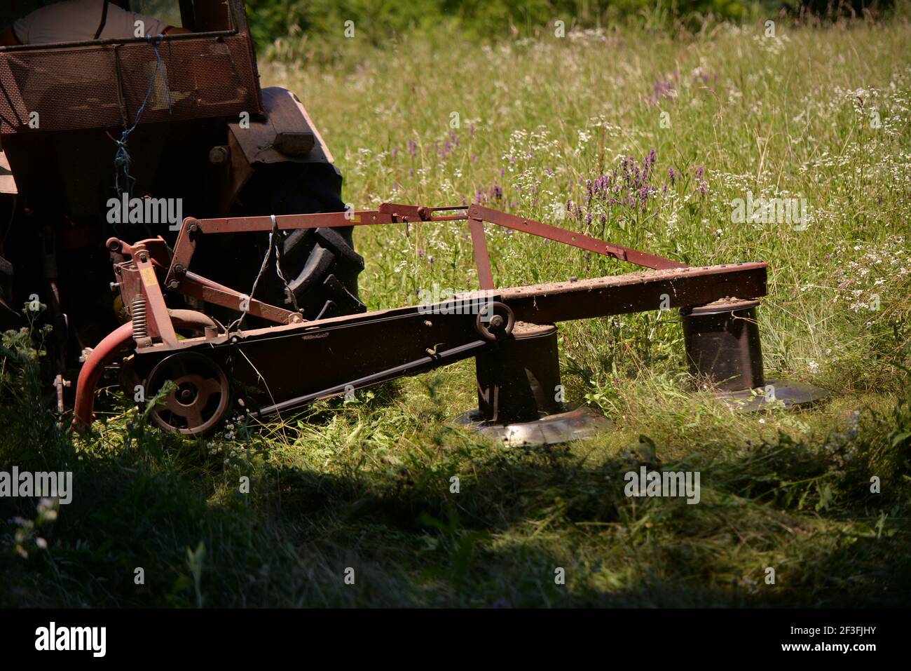 An industrial tractor cutting grass on a field Stock Photo - Alamy