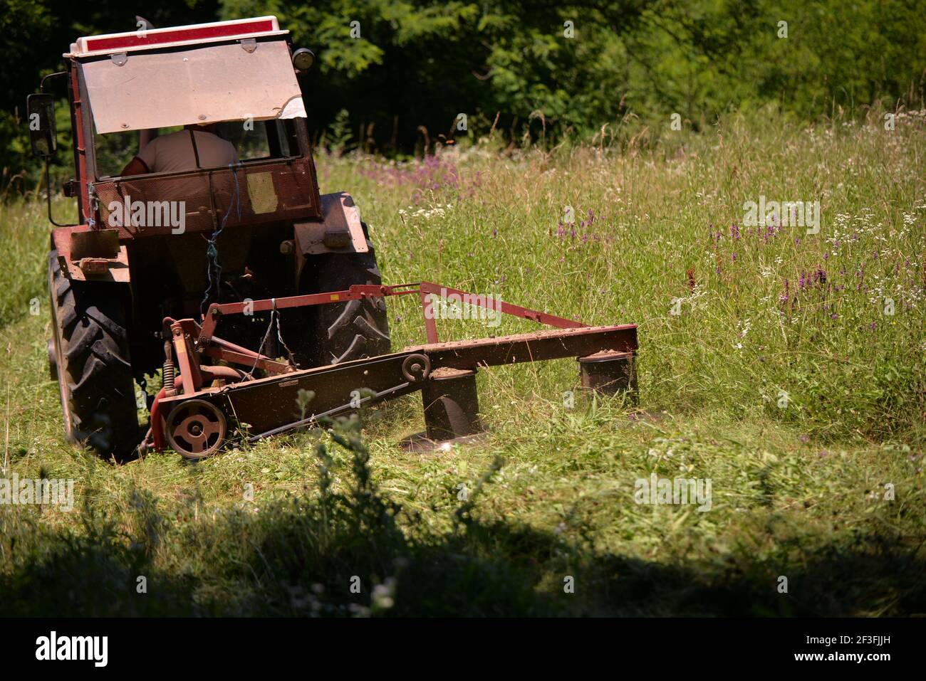 An industrial tractor cutting grass on a field Stock Photo - Alamy