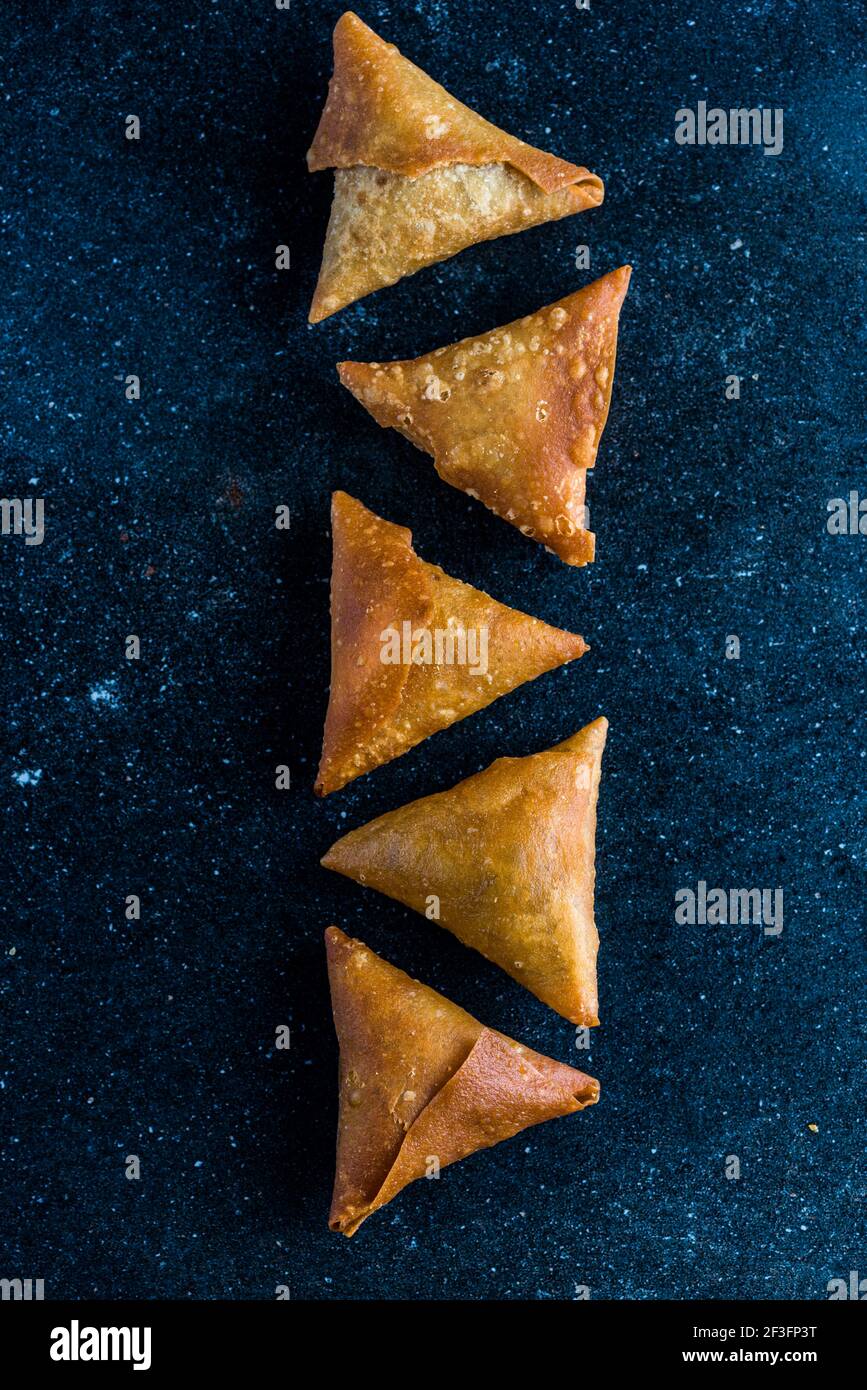 Triangular samosas on a blue glossy surface Stock Photo - Alamy