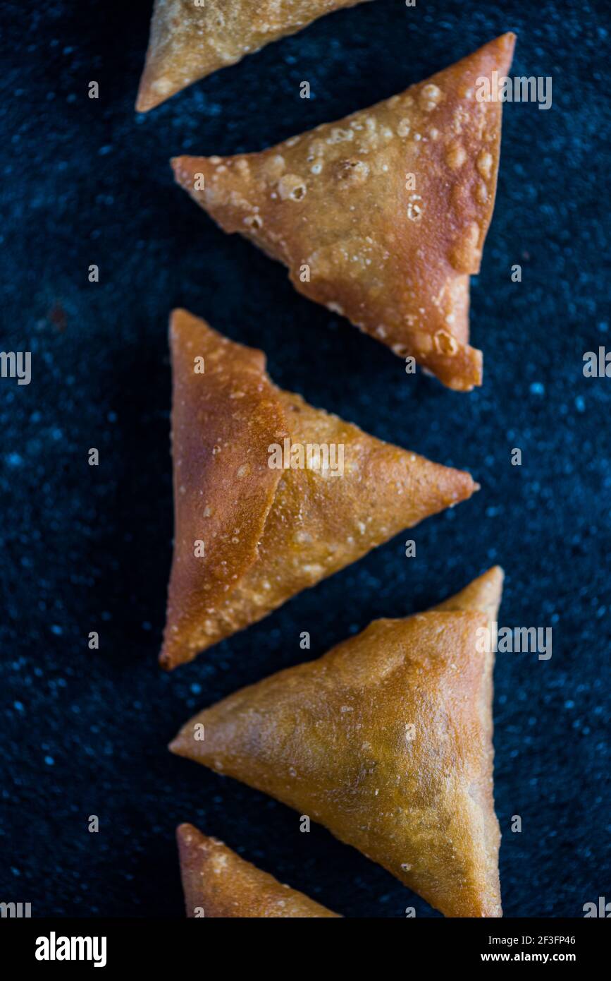 Samosa triangles placed in a pattern on a black surface Stock Photo - Alamy