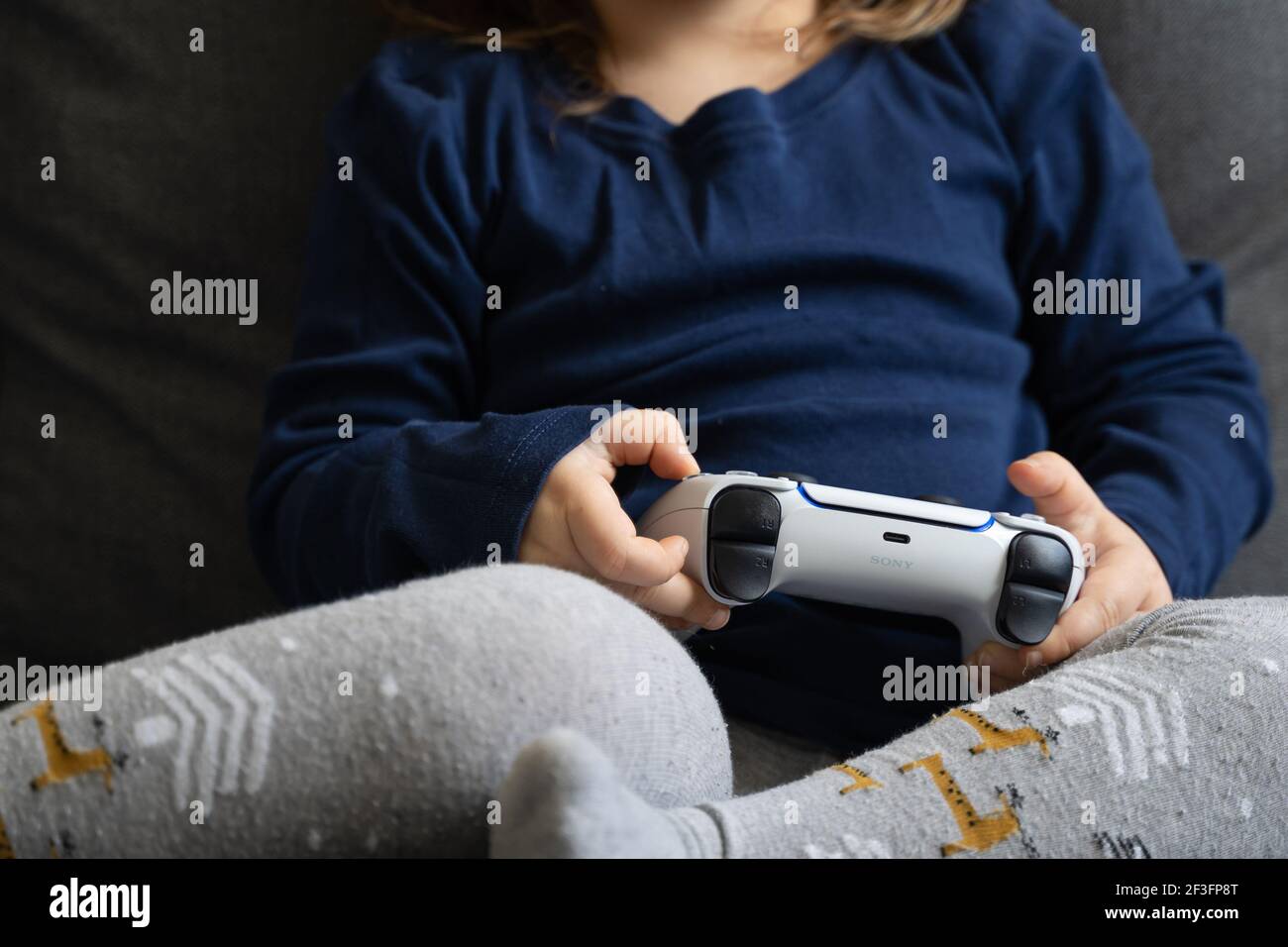 Toddler girl playing video game console at home in living room on the ...