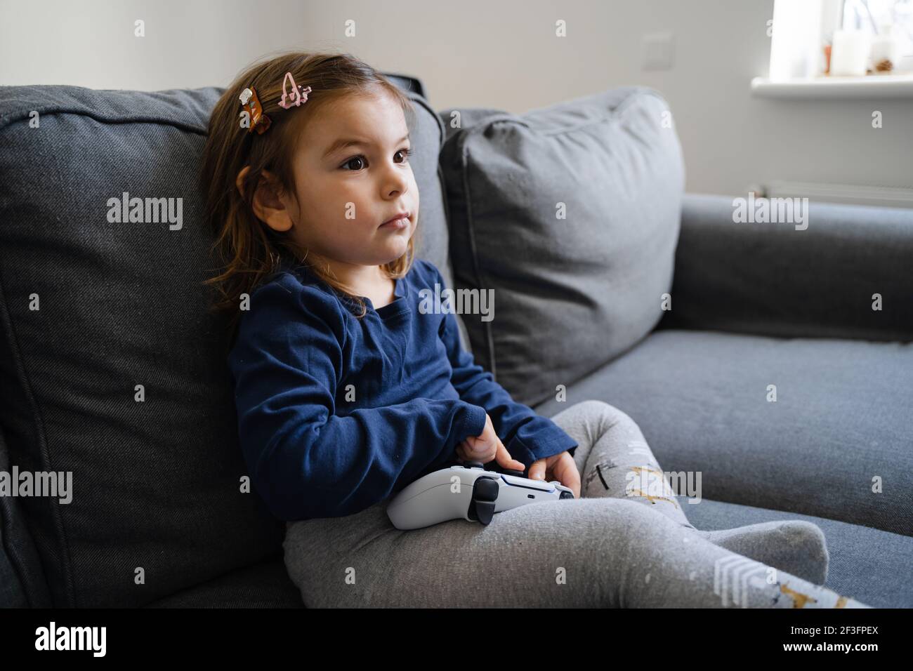 Toddler girl playing video game console at home in living room on the ...