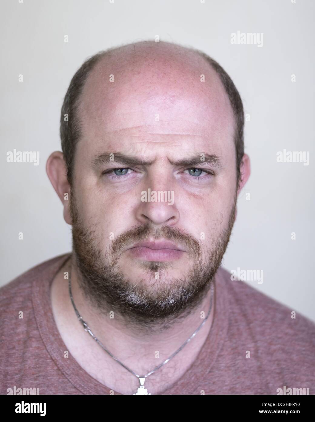 A vertical shot of a male making an angry face on a white background ...