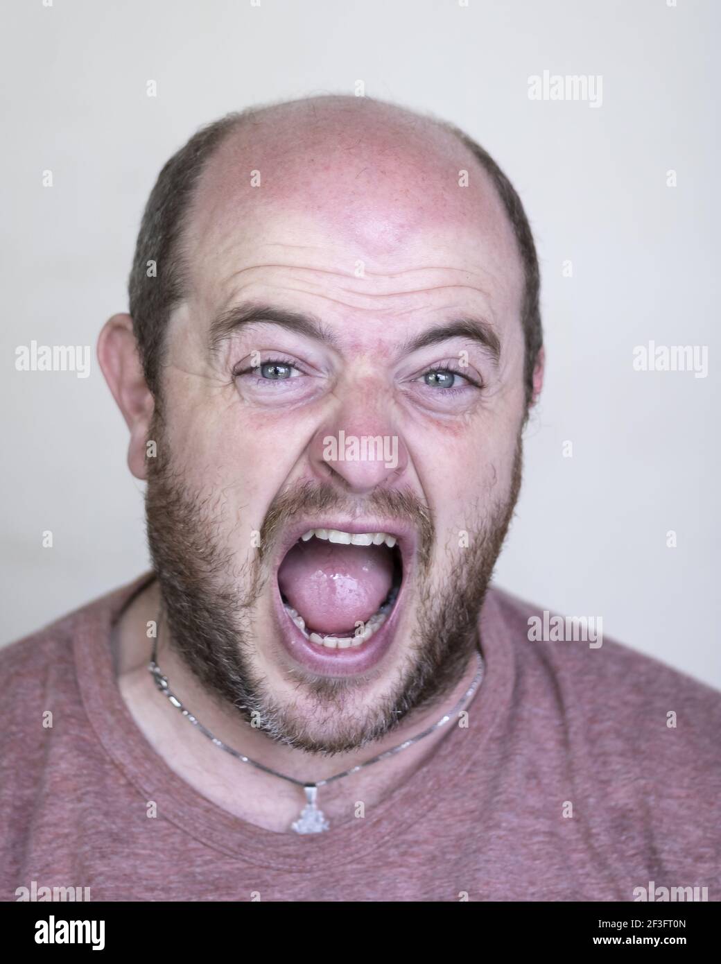 A vertical shot of a male making a funny face on a white background ...