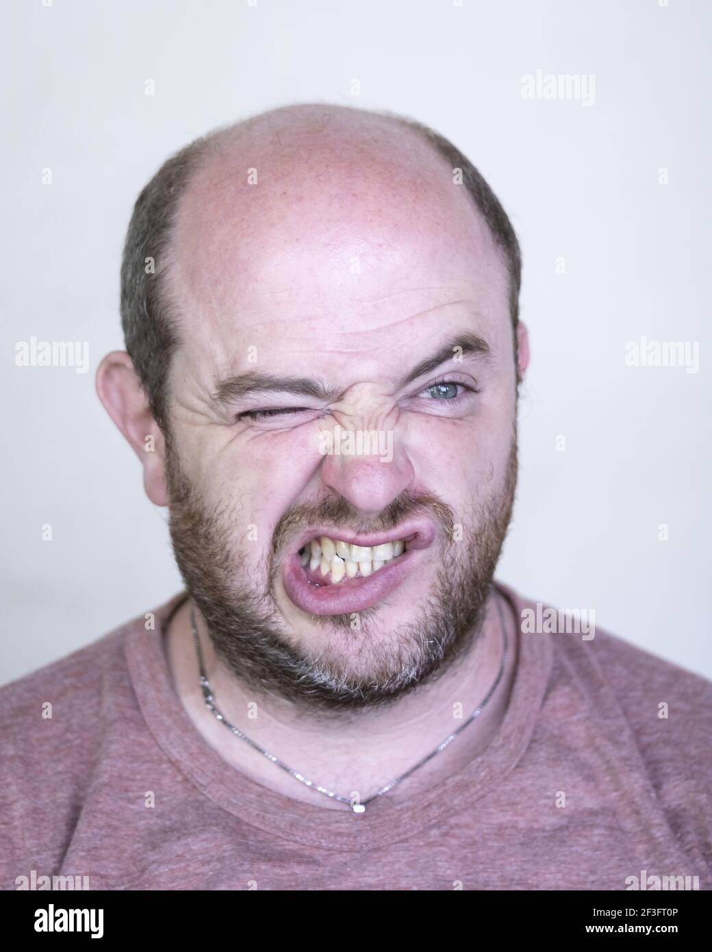 A vertical shot of a male making a funny face on a white background ...