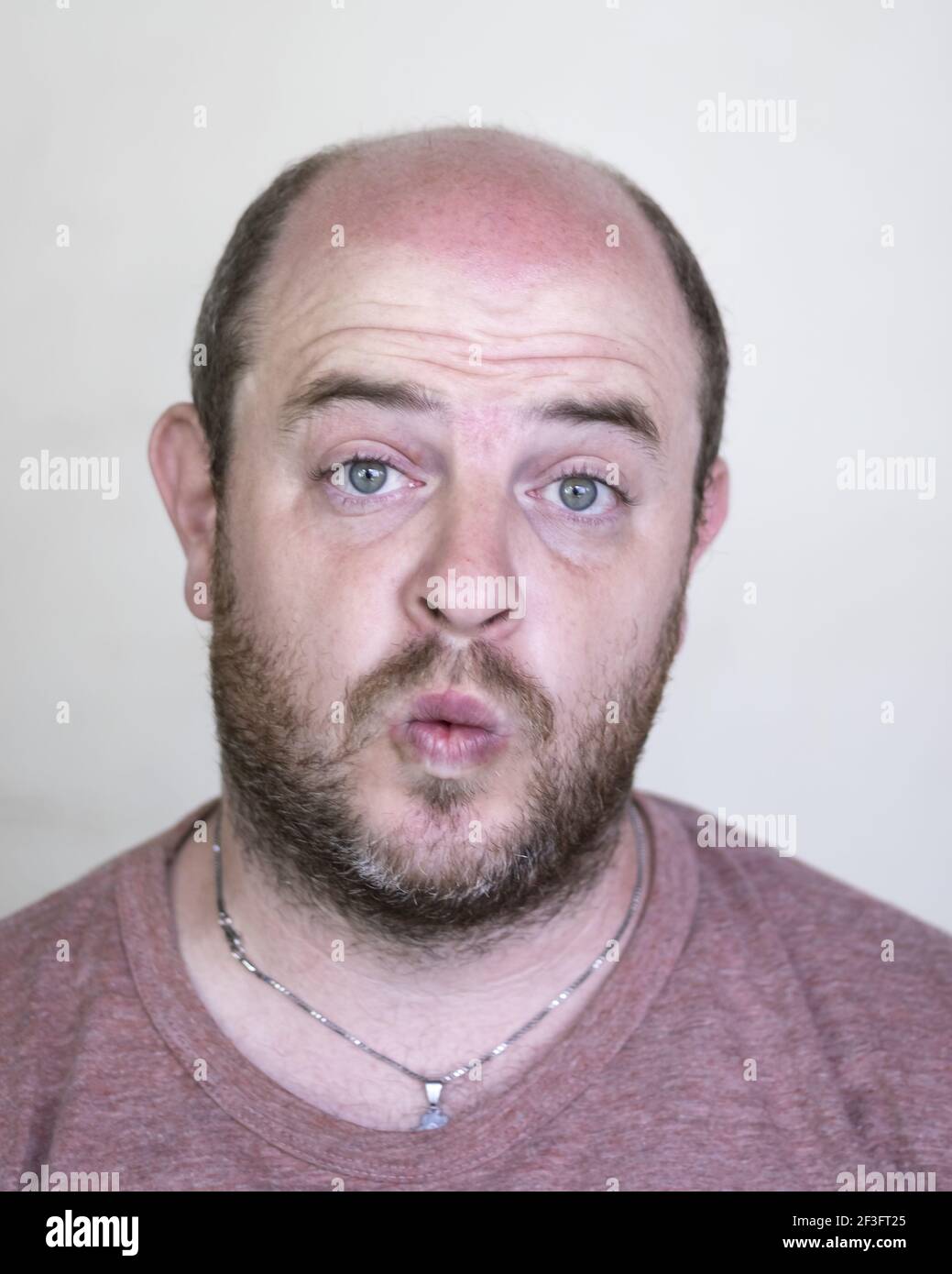 A vertical shot of a male making a funny face on a white background ...