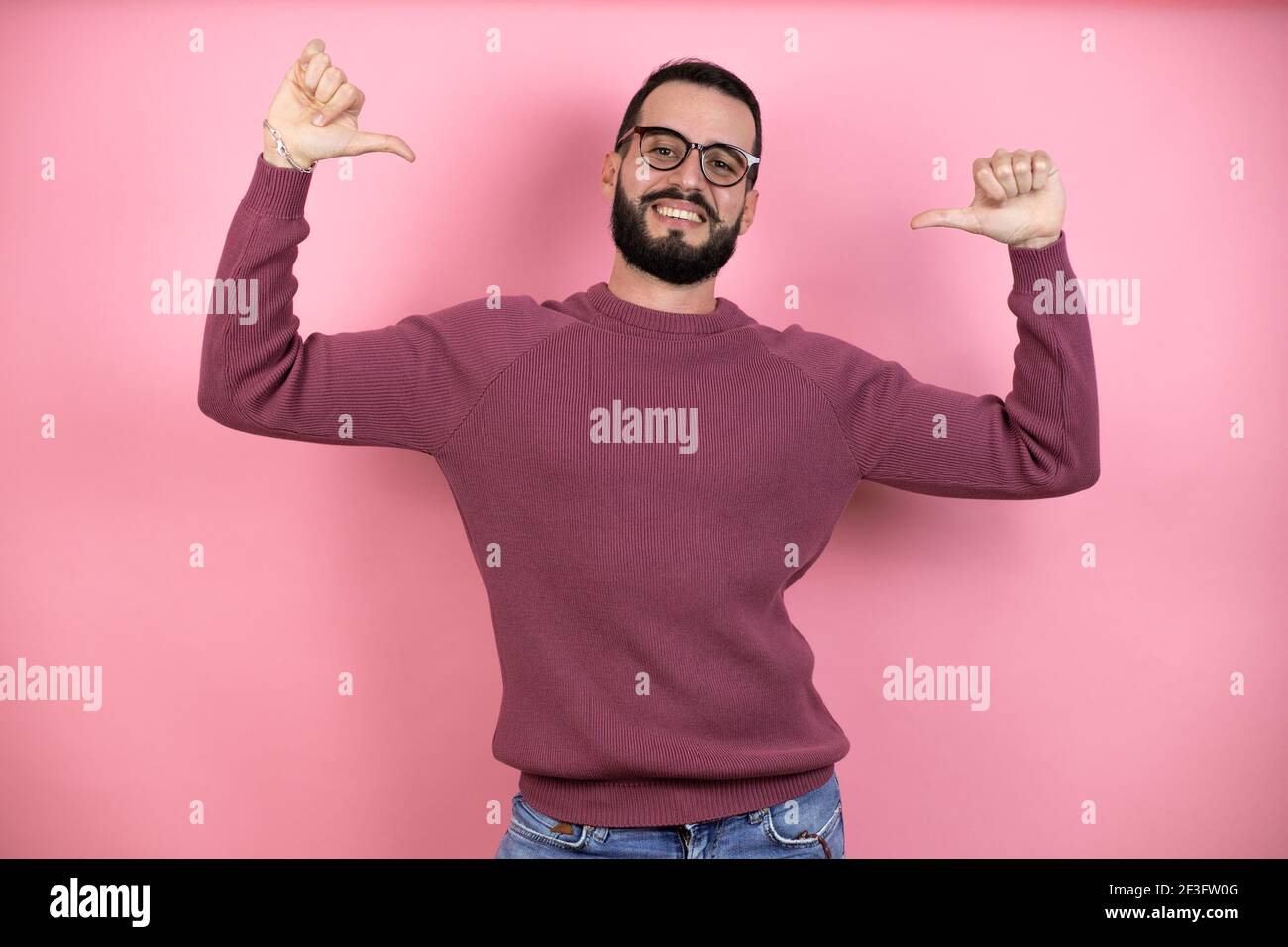 Handsome man wearing glasses and casual clothes over pink background ...