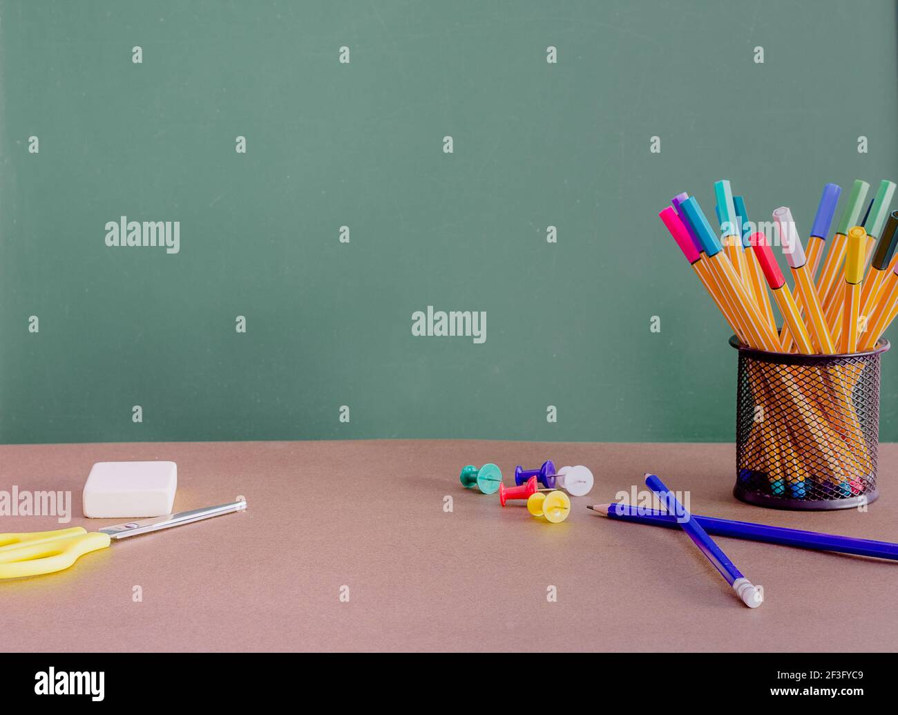 A green chalkboard with space for text behind the desk with colorful ...