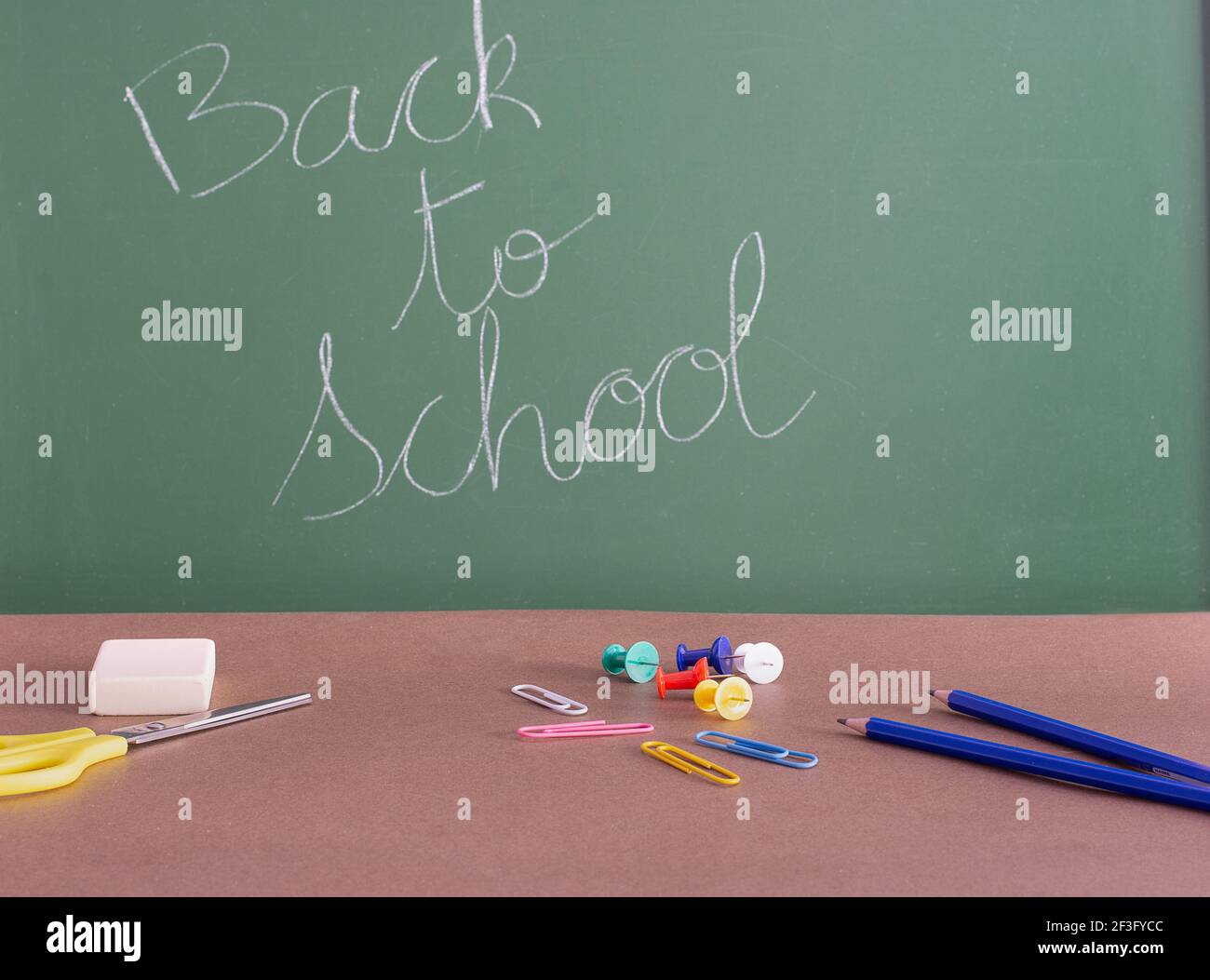 The phrase "back to school" written on a green chalkboard behind the ...