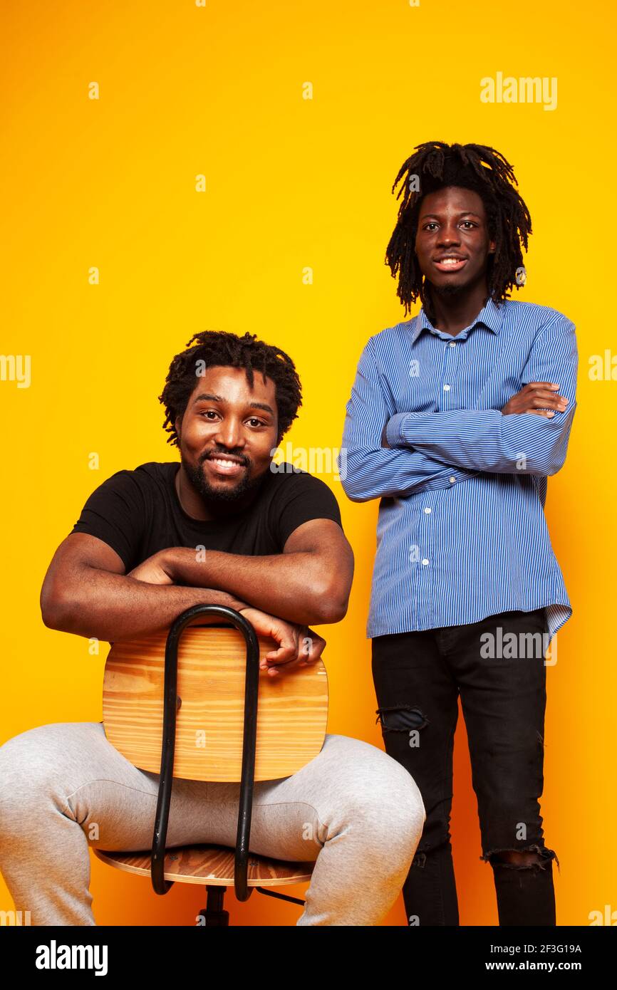 two african american guys posing cheerful together on yellow background ...